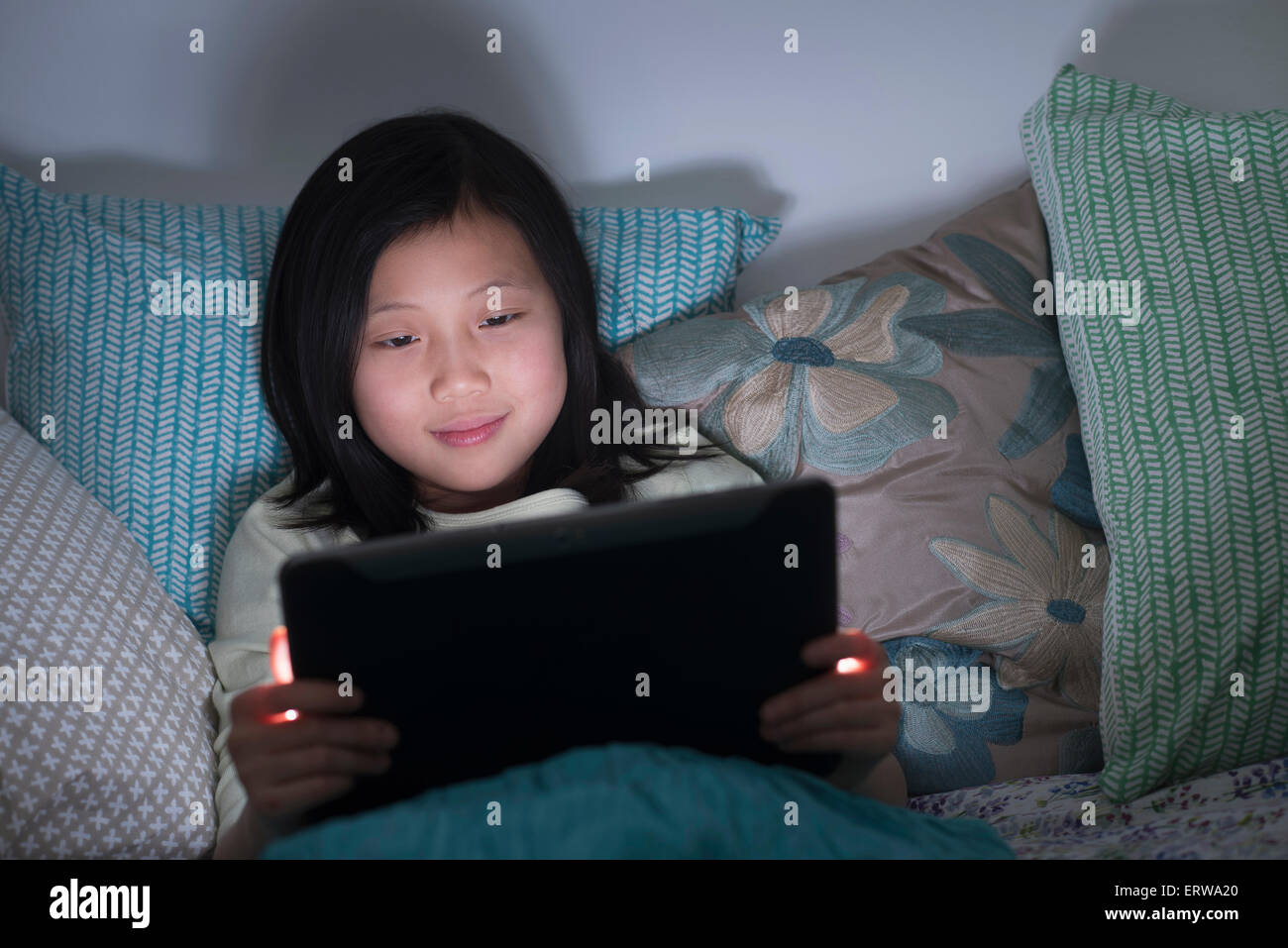 Smiling Chinese girl watching digital tablet in bed Stock Photo - Alamy