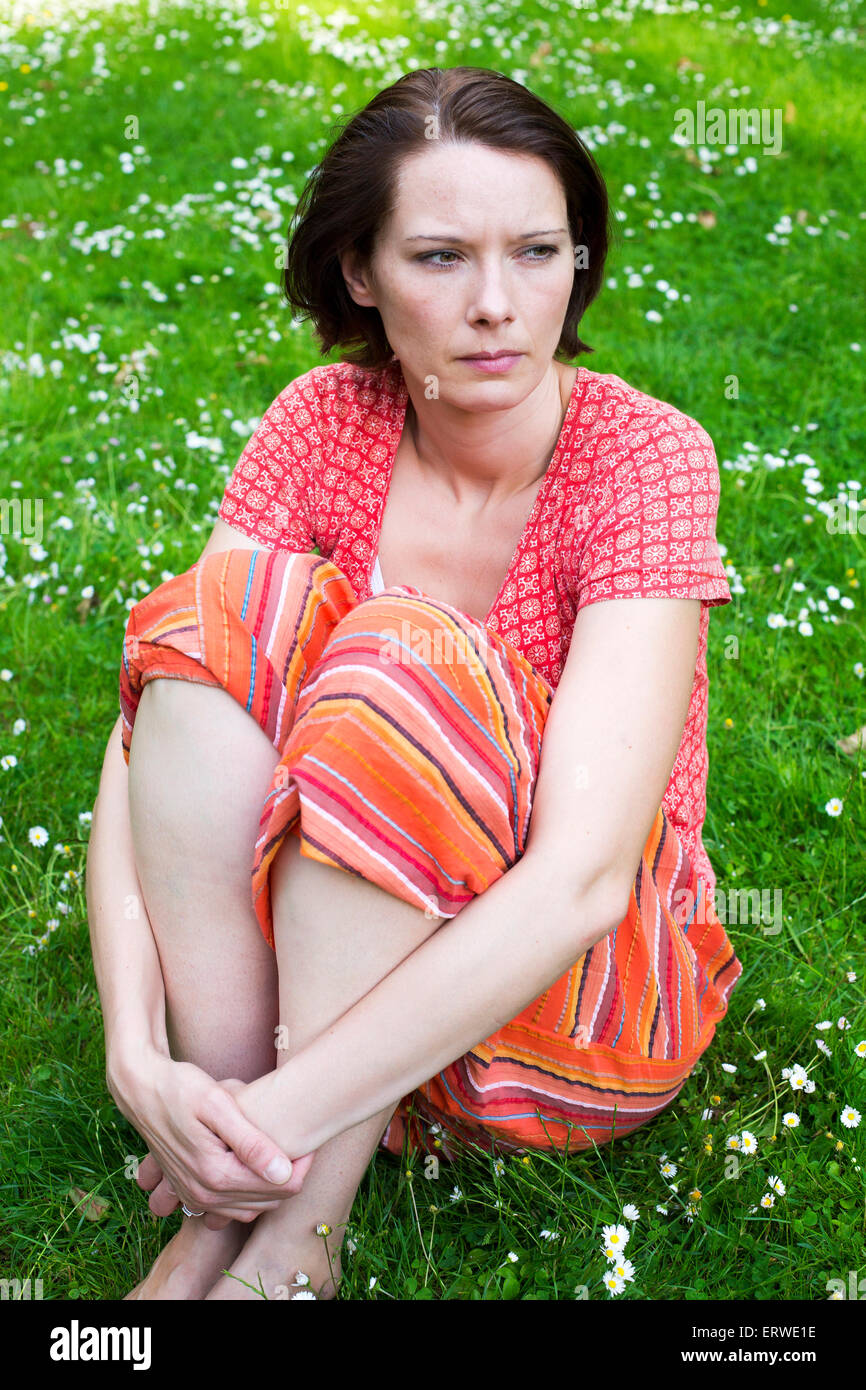 woman sitting on grass looking thoughtfully Stock Photo - Alamy