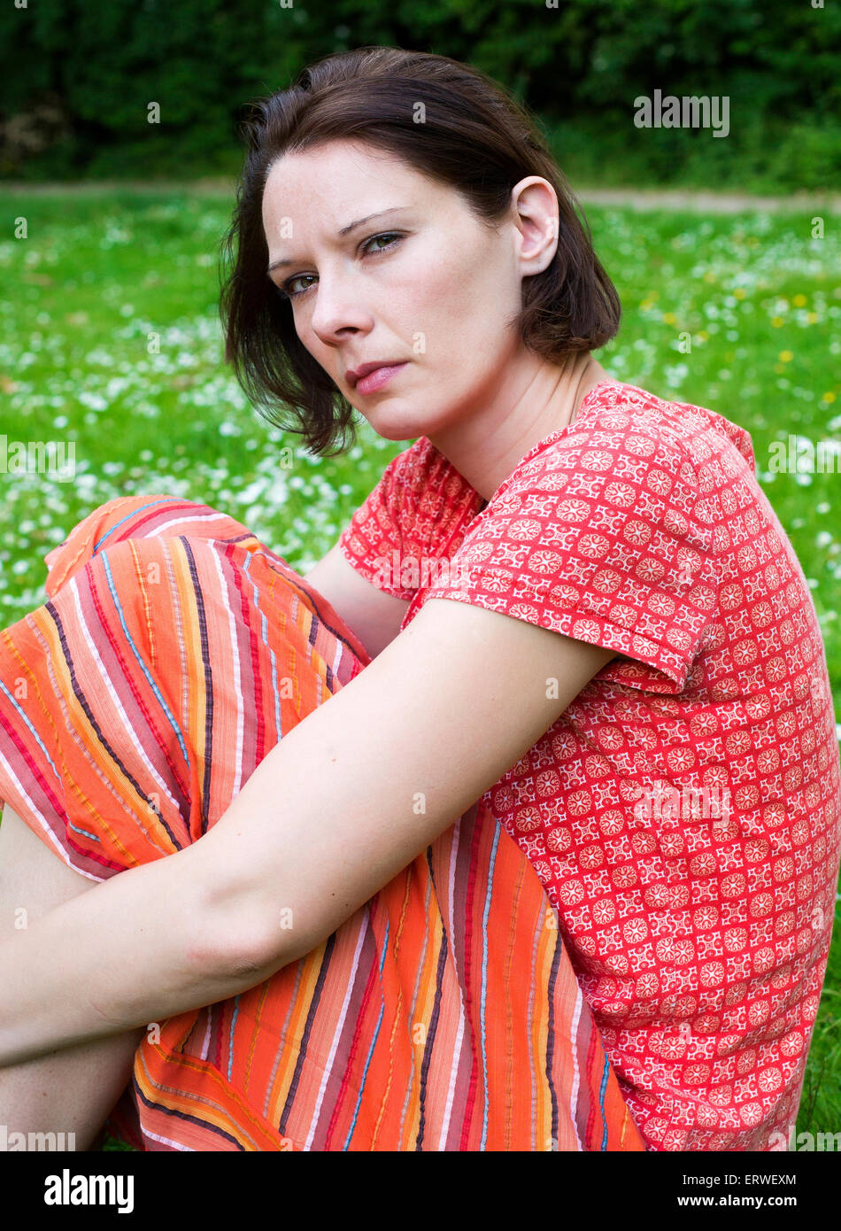 woman sitting on grass looking thoughtfully Stock Photo - Alamy