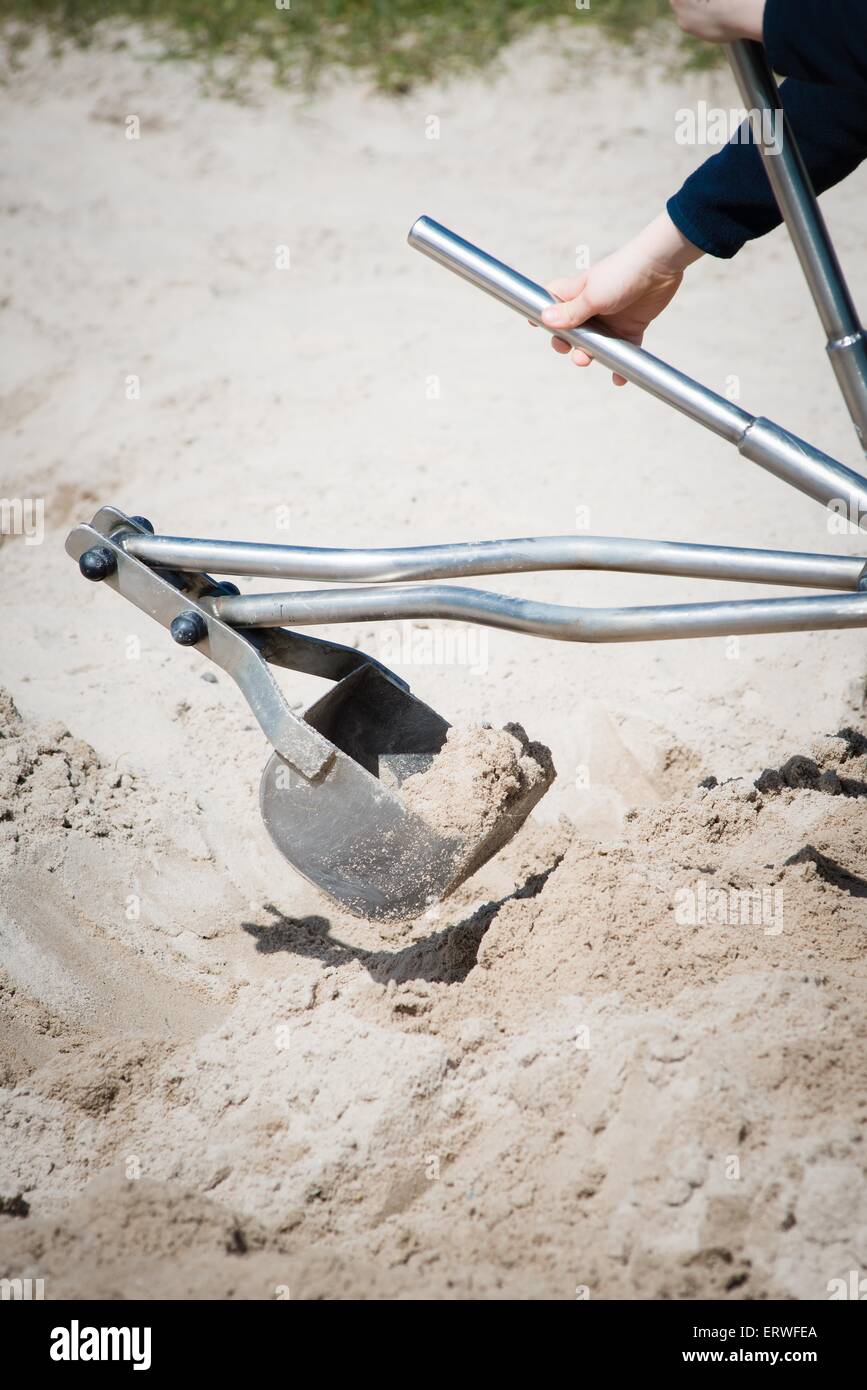 Kid playing with metal digger at kids play area in sand Stock Photo - Alamy