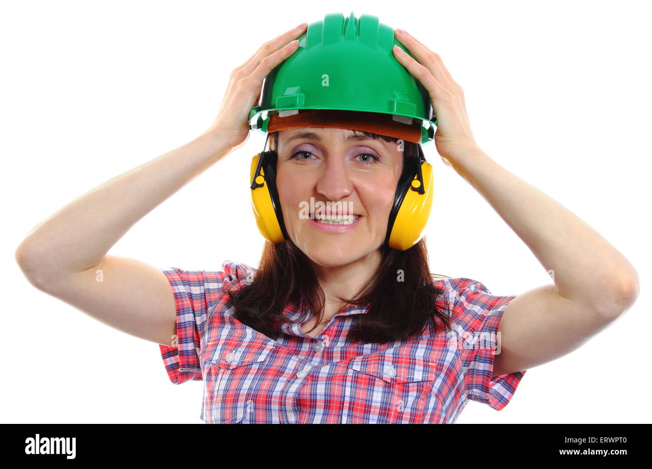 Shocked female construction worker wearing green helmet and protective headphones, safety at ...