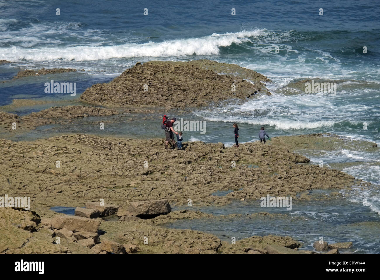 People on rocky foreshore below cliff Stock Photo - Alamy