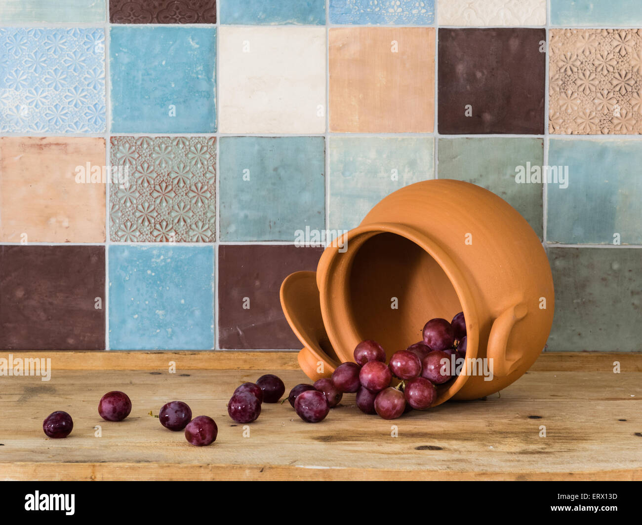 Red grapes rolling out from a ceramic pot Stock Photo - Alamy