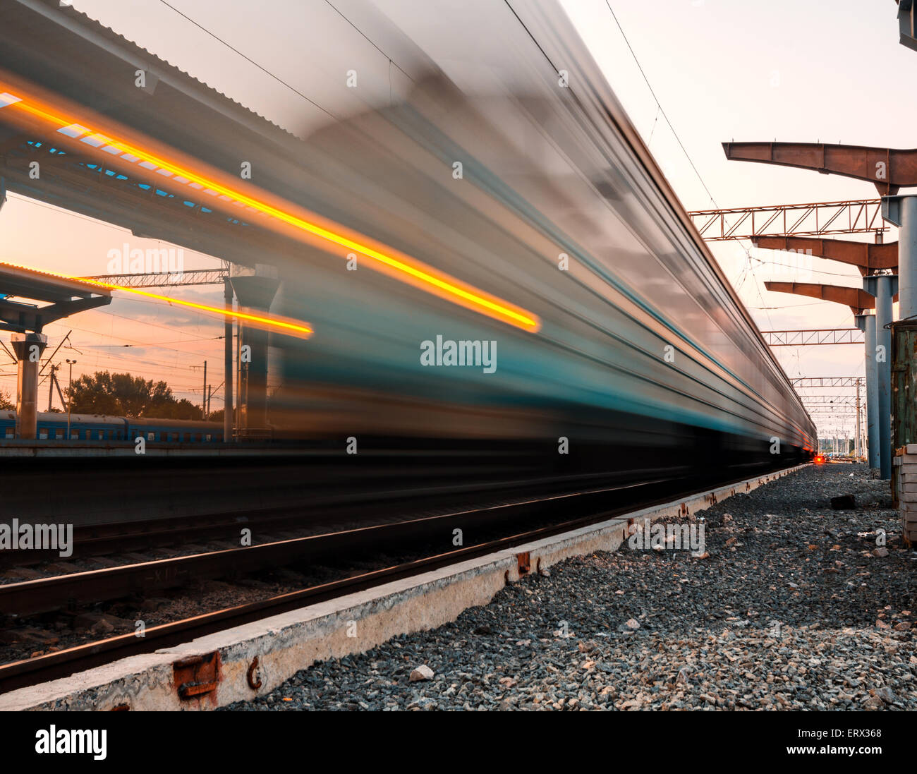 High speed passenger train on tracks with motion blur effect at sunset ...