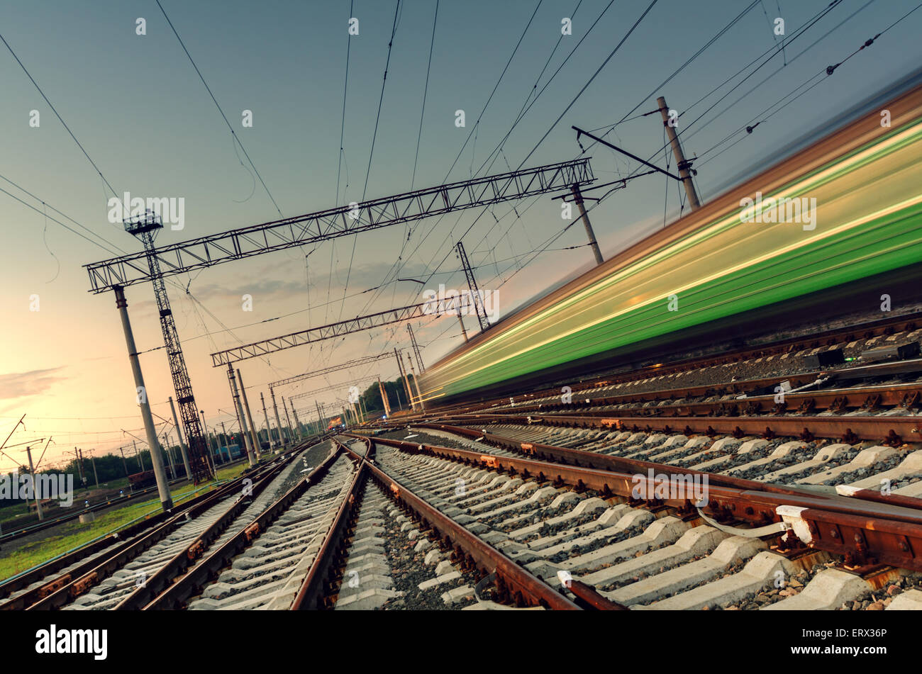 High speed passenger train on tracks with motion blur effect at sunset ...