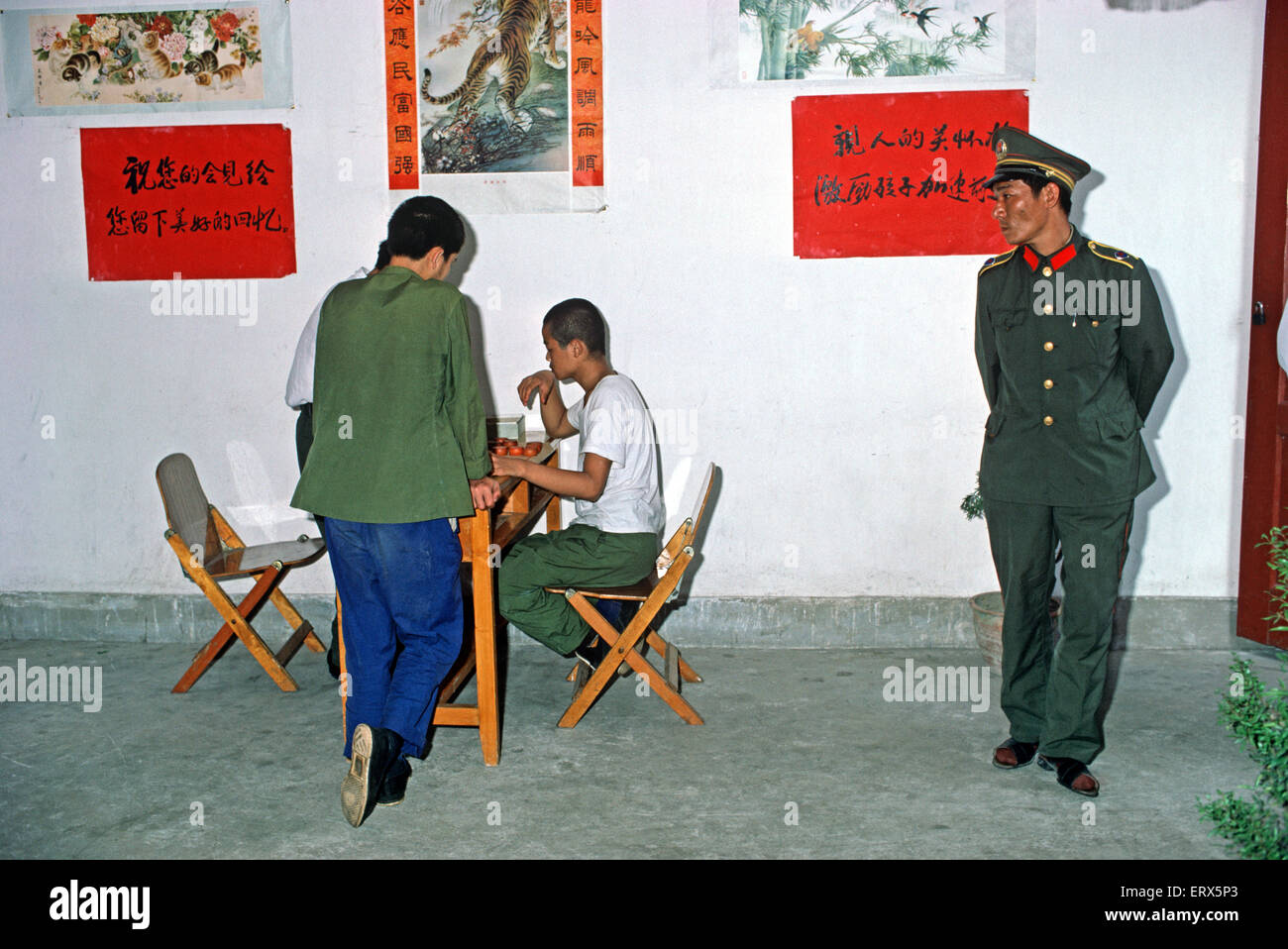 Prison guard watching over prisoners in recreation area of Chinese ...