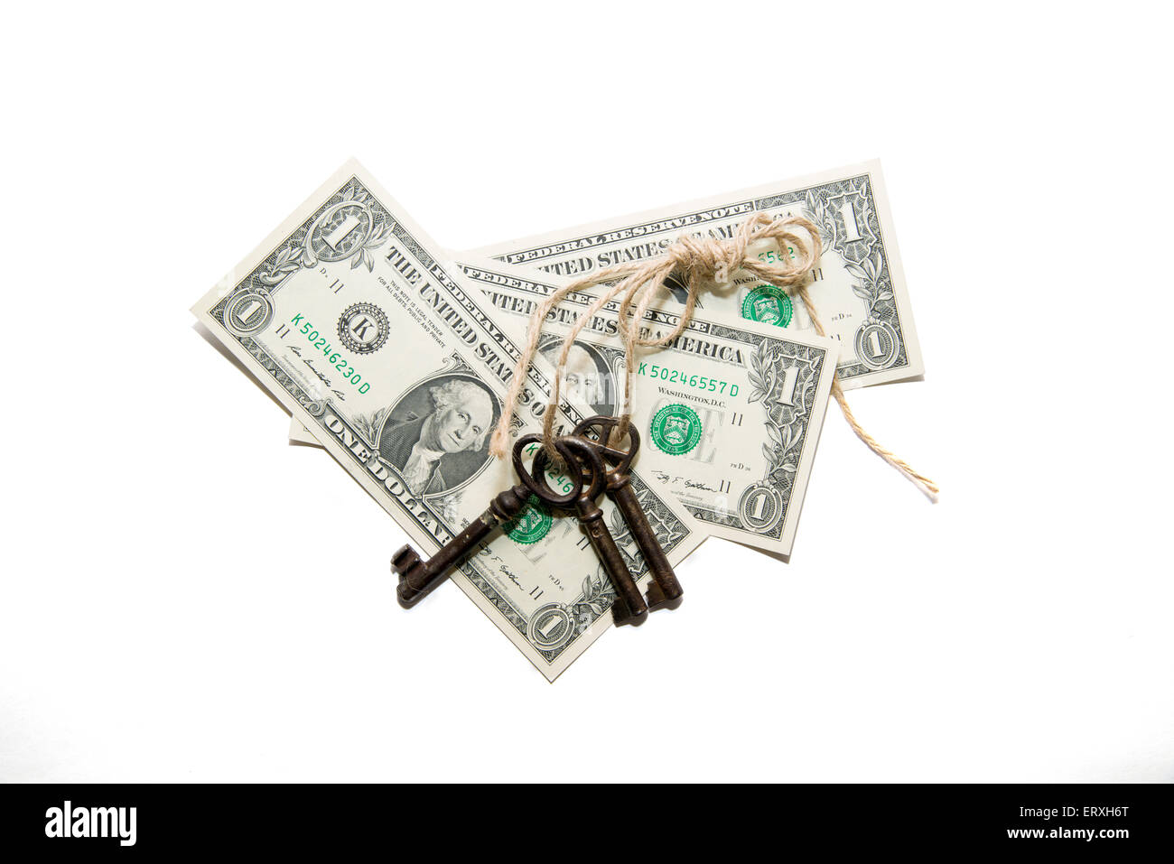 Keys tied with a rope and a few dollars banknotes on a white background ...
