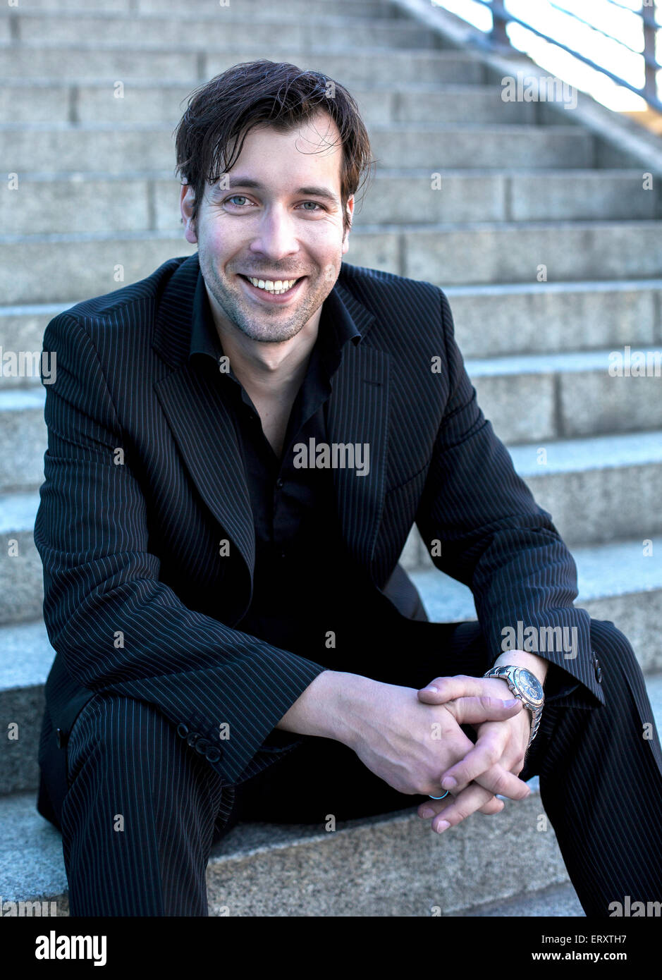 businessman sitting outside on stairs and smiling into camera Stock ...
