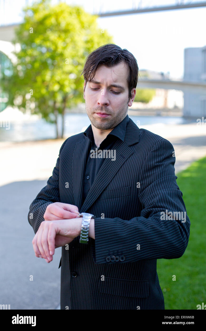 businessman waiting outside and looking at his watch Stock Photo - Alamy