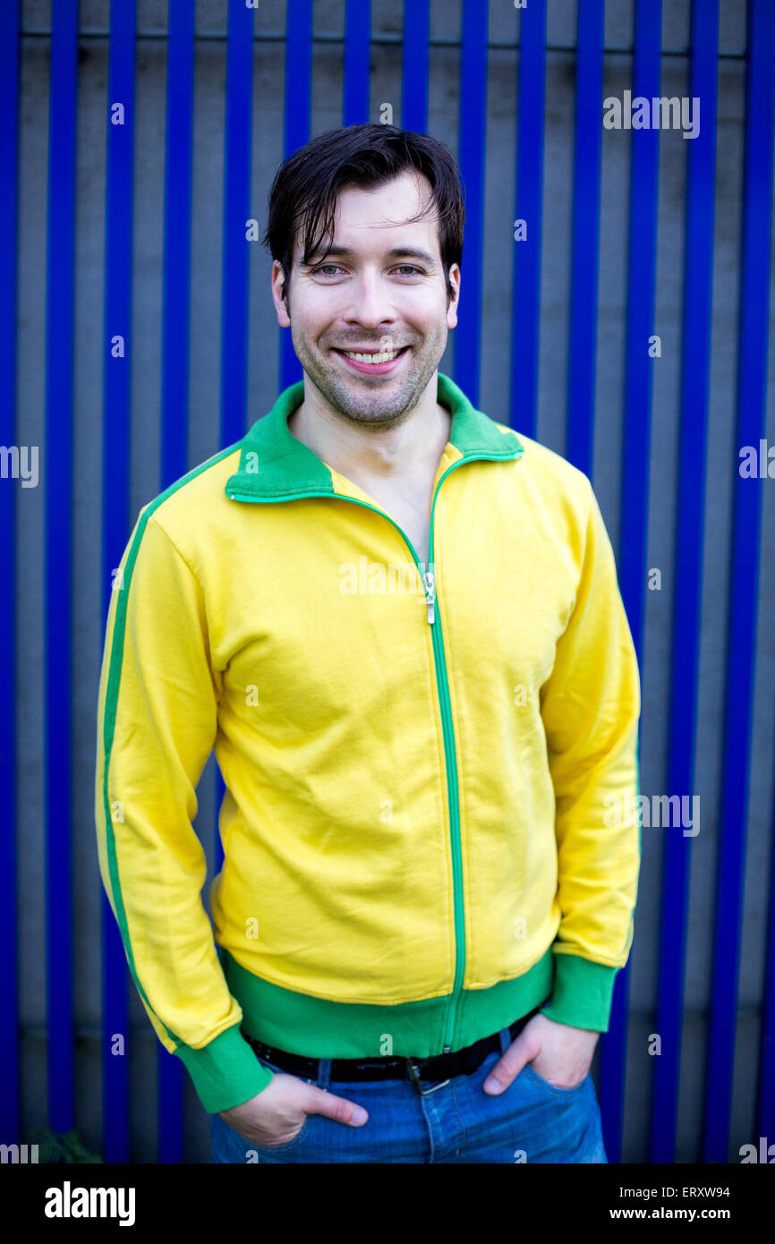 portrait of man in yellow trickot in front of blue wall Stock Photo - Alamy