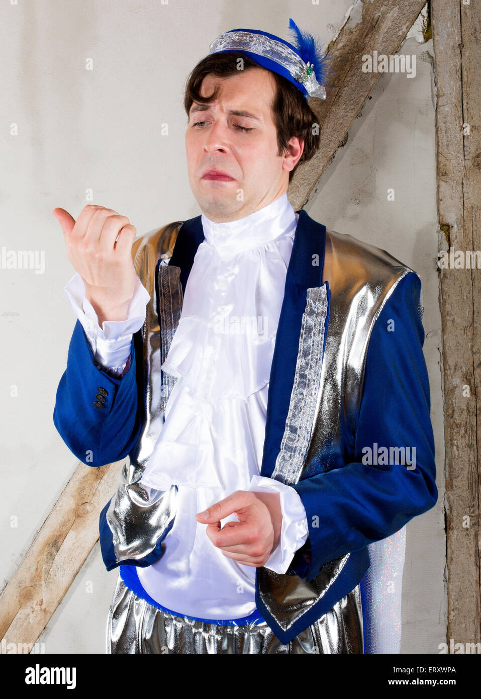 man dressed as a prince with a blue hat is looking at his hand Stock ...