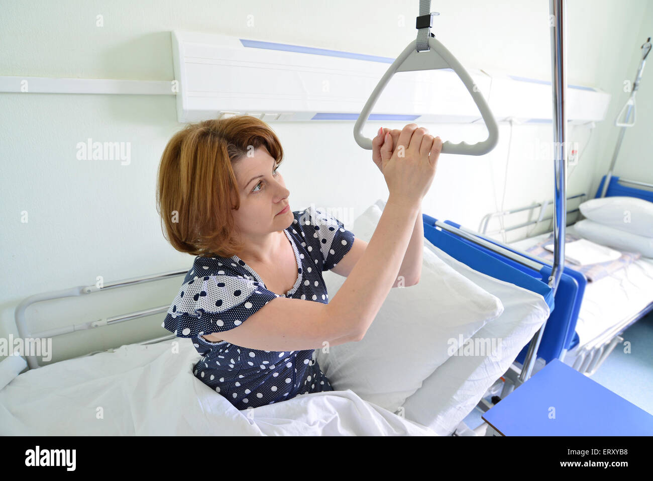 Female patient holding on to a device for lifting in hospital room ...