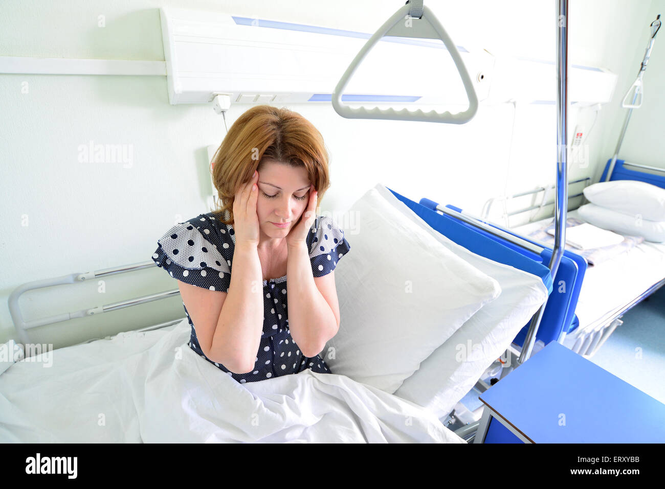 Female patient with headache on a bed in hospital ward Stock Photo - Alamy
