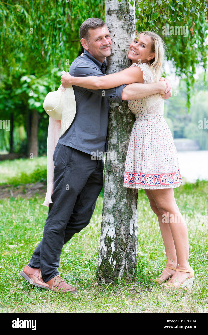 couple standing in park and hugging a tree Stock Photo - Alamy
