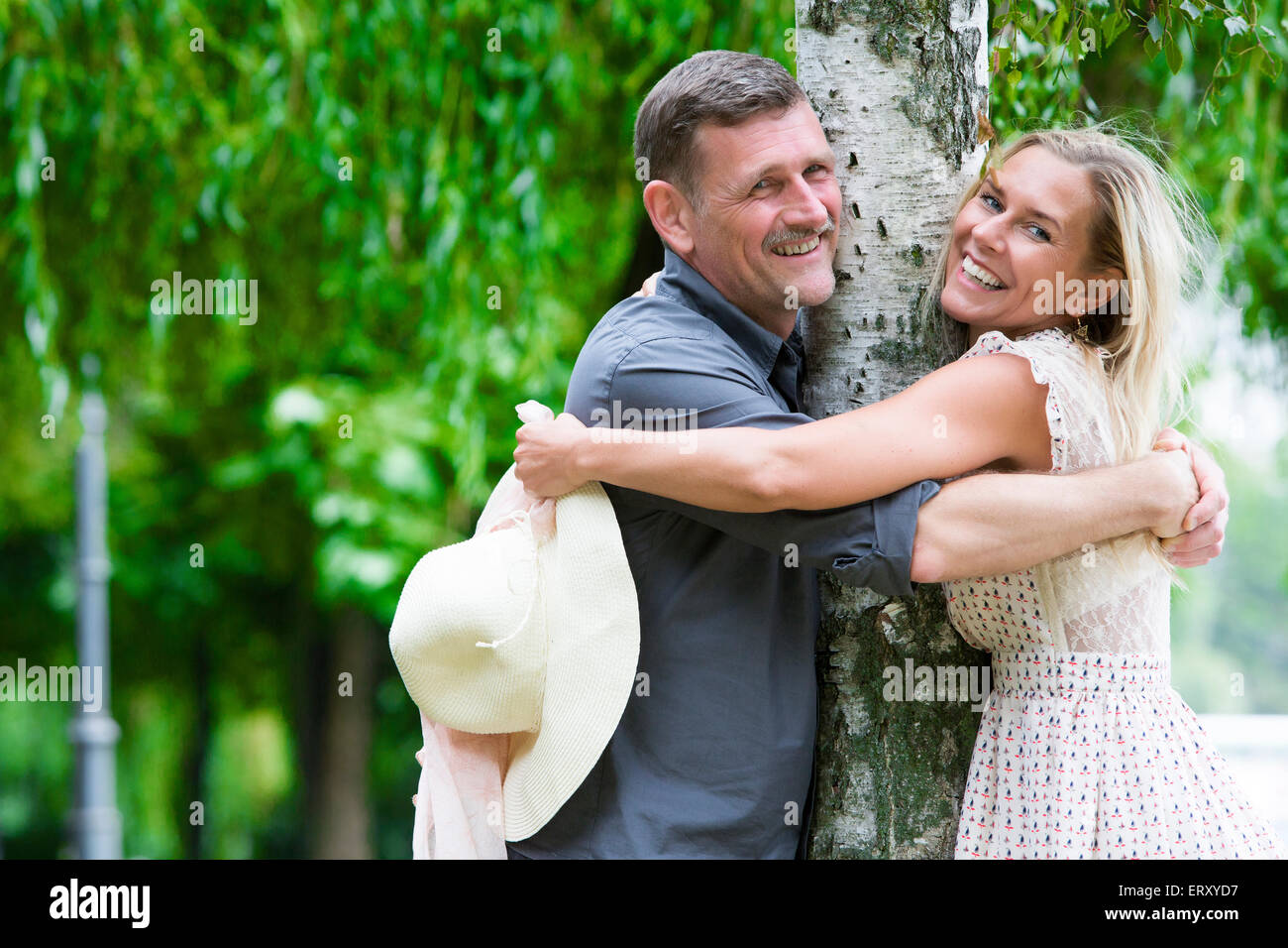 couple standing in park and hugging a tree Stock Photo - Alamy