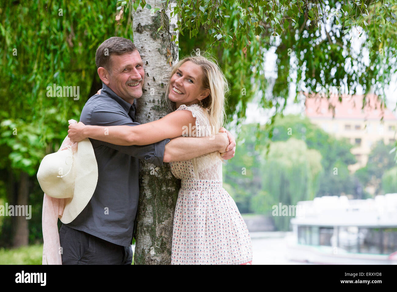 couple standing in park and hugging a tree Stock Photo - Alamy