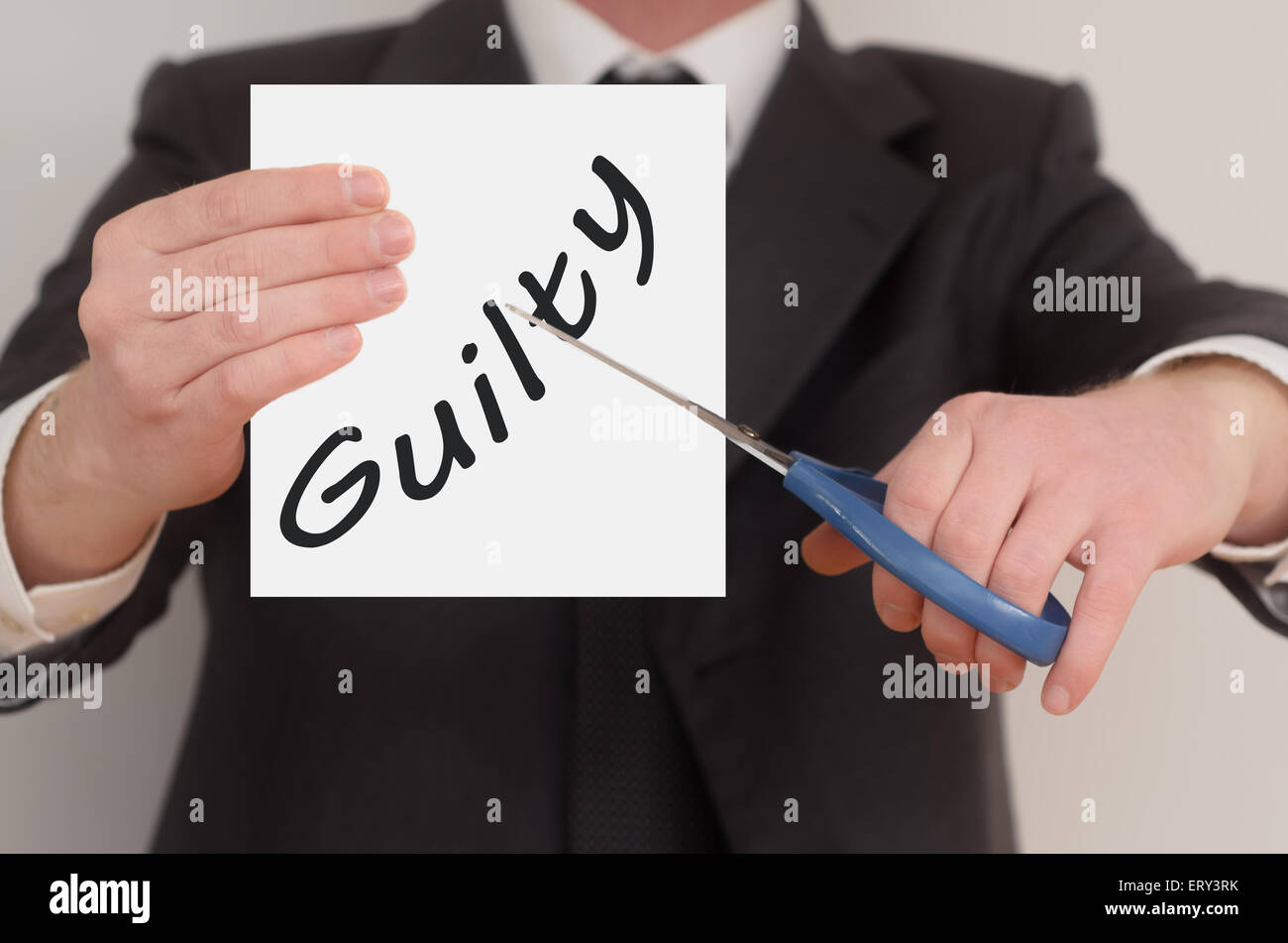 Guilty, man in suit cutting text on paper with scissors Stock Photo - Alamy