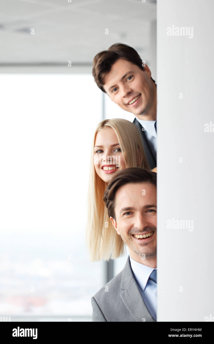 Happy business people looking out from corner in office Stock Photo - Alamy