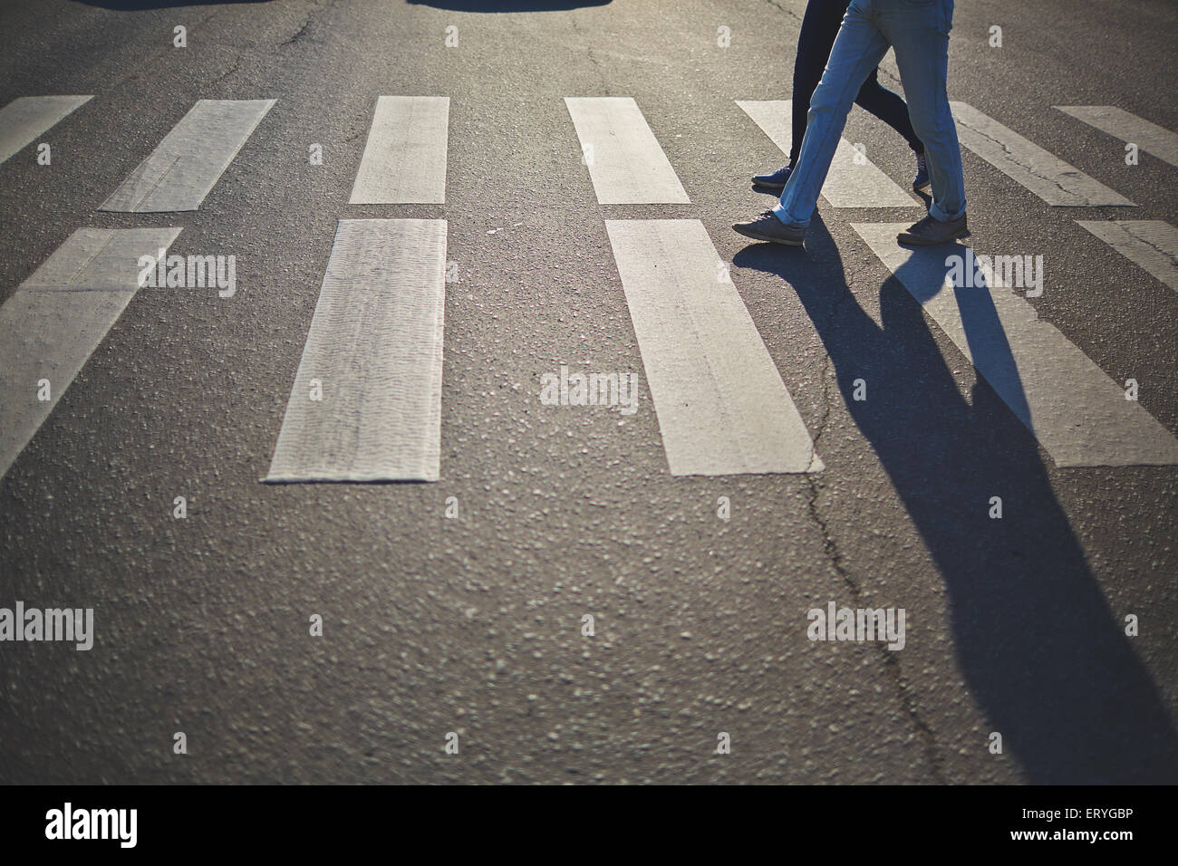 Urban couple in jeans and sports shoes crossing road Stock Photo - Alamy