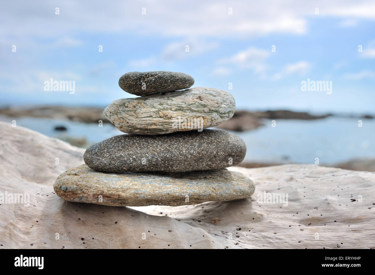 pebbles stacked on piece of wood on the seaside Stock Photo - Alamy
