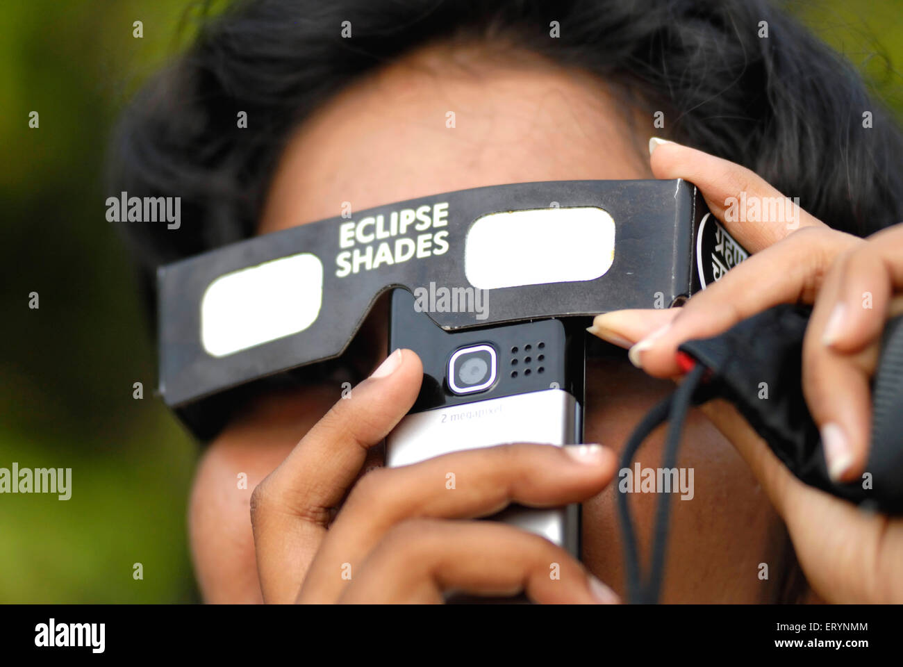 A young girl taking picture cell phone watches partial solar eclipse by ...