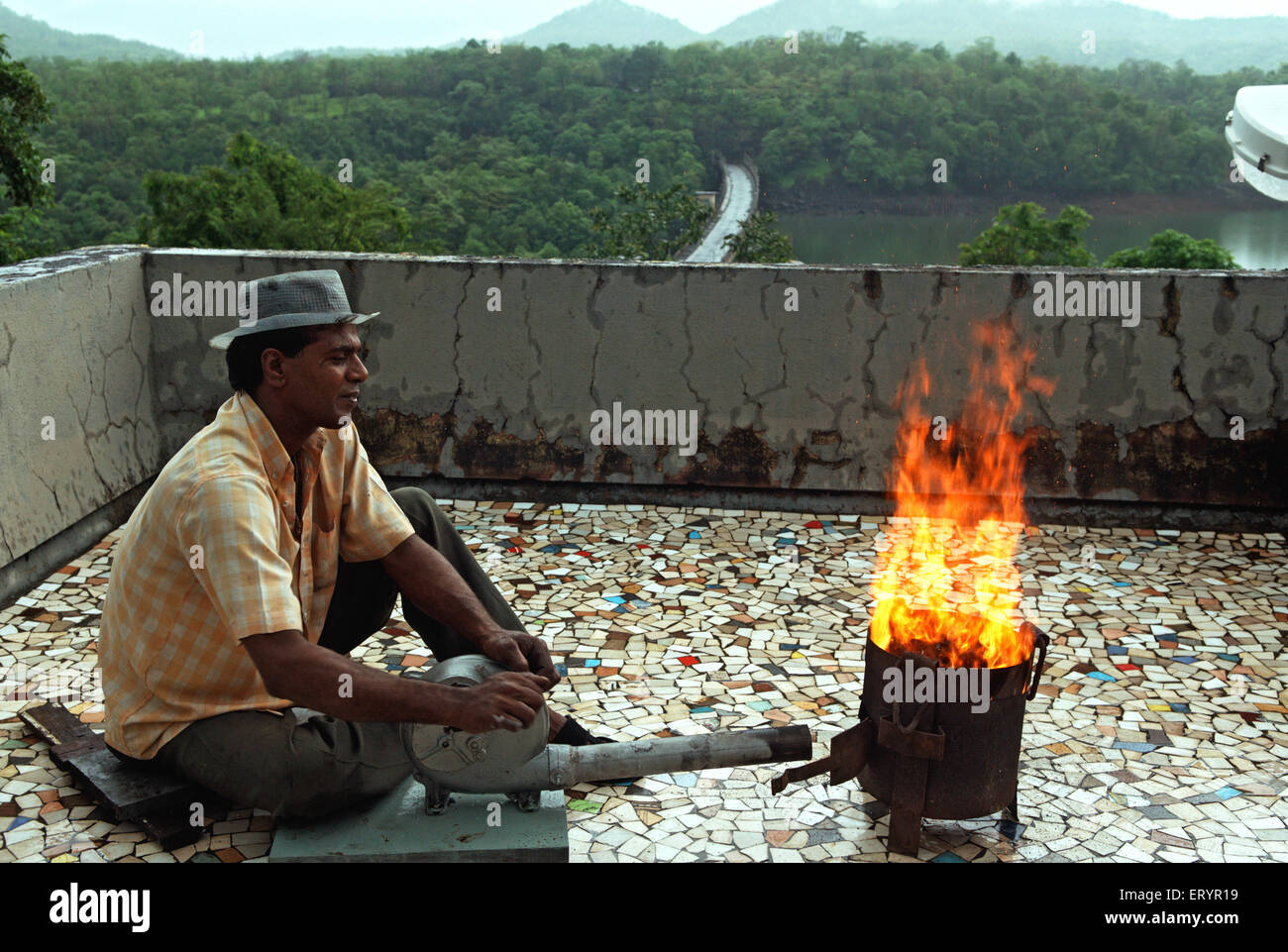 Blowing air to ignite coal stove , Bombay , Mumbai ; Maharashtra ...