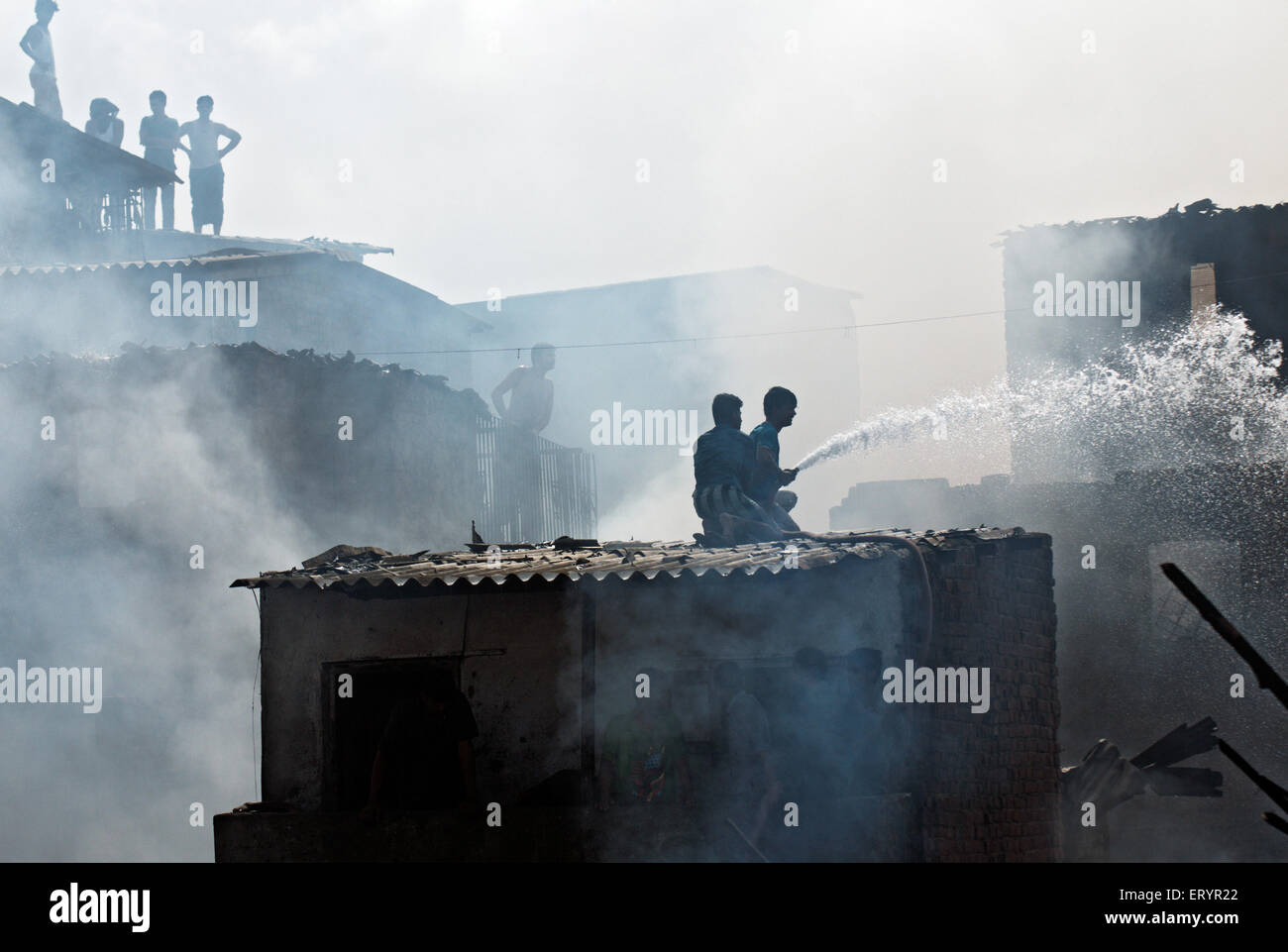 Dwellers dousing fire in Behrampada slums ; Bandra ; Bombay Mumbai ...