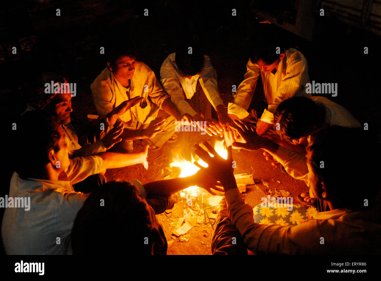 People sitting around bonfire warming hands in winter season , Bombay ...
