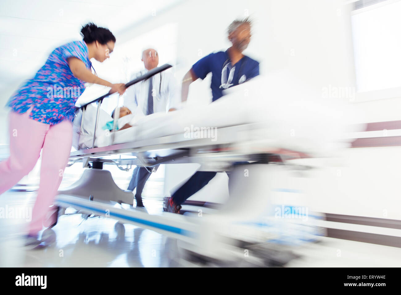 Doctors and nurse rushing patient in stretcher in hospital corridor ...