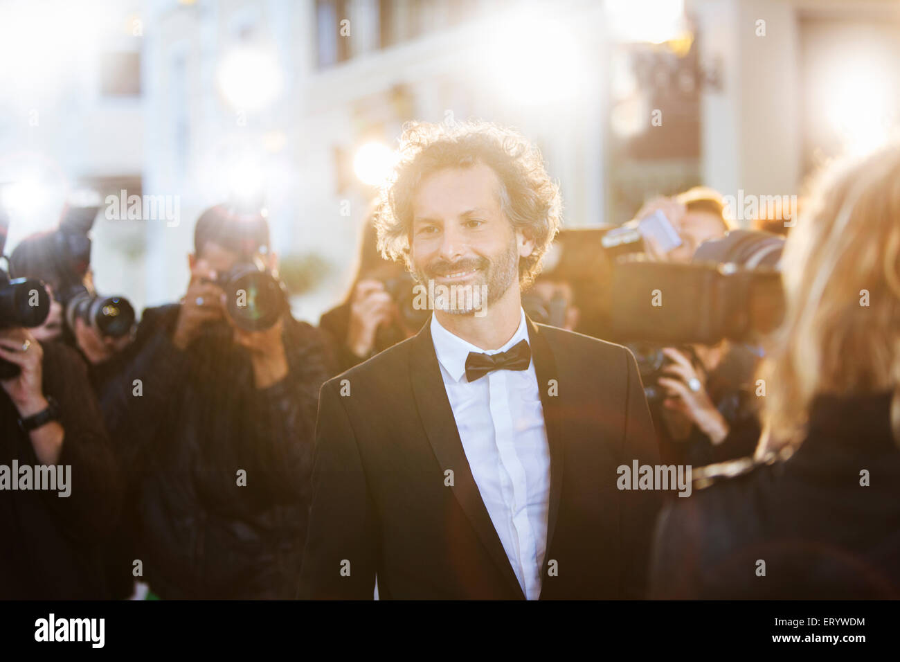 Smiling celebrity being photographed by paparazzi at event Stock Photo ...