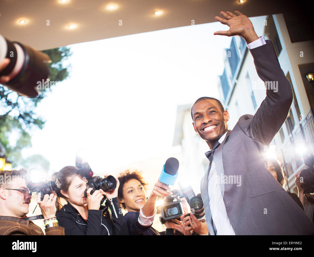 Waving celebrity being interviewed and photographed by paparazzi at ...