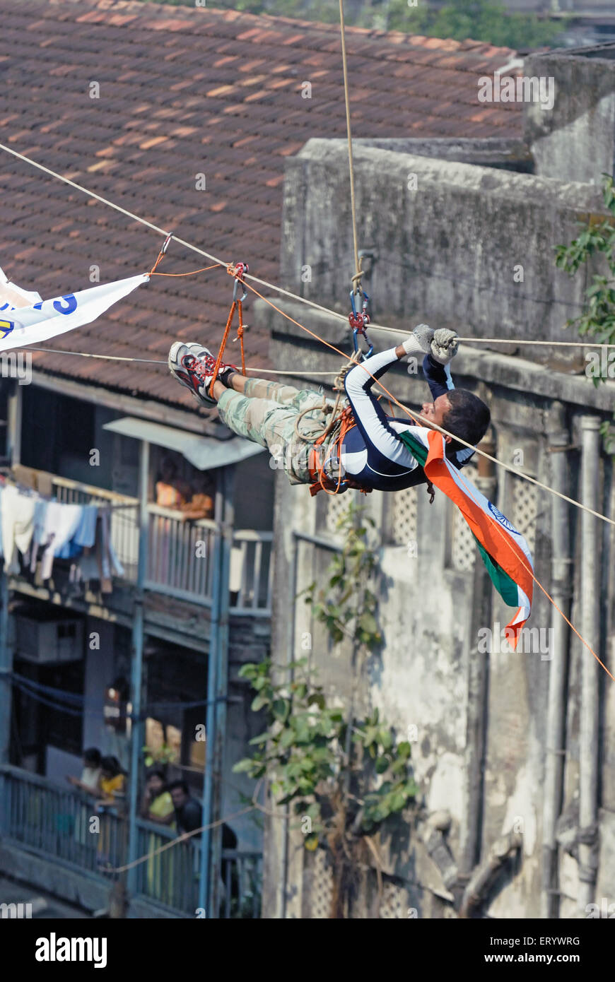 Man crossing between two buildings on rope ; Bombay ; Mumbai ...