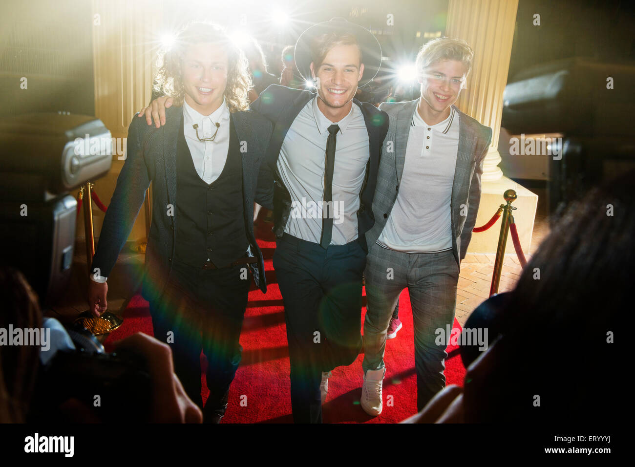 Portrait of smiling celebrities in a row arriving at red carpet event ...
