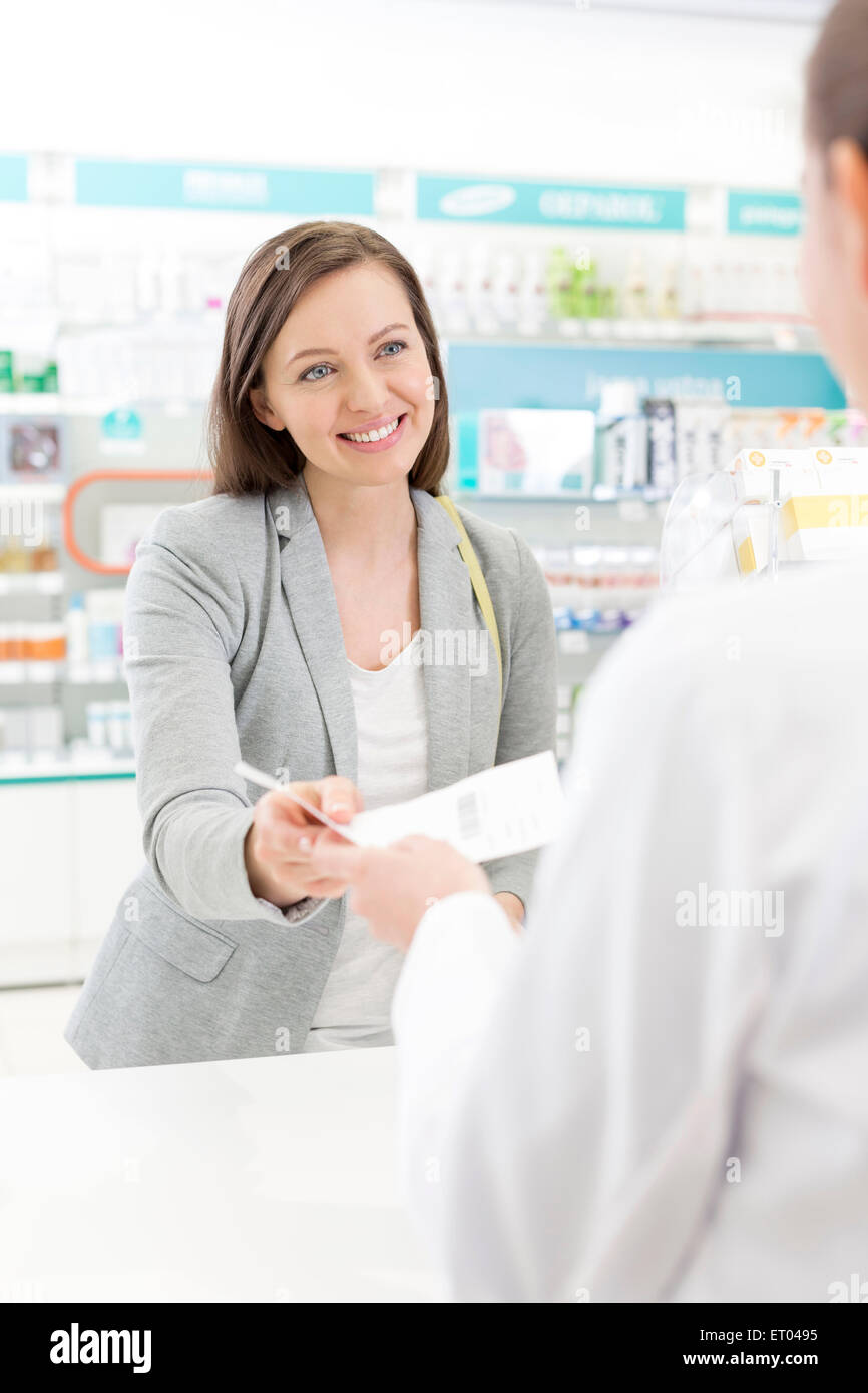 Smiling customer giving prescription to pharmacist in pharmacy Stock ...