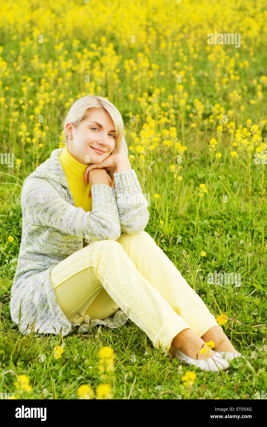 Beautiful young woman sitting in a flower field Stock Photo - Alamy