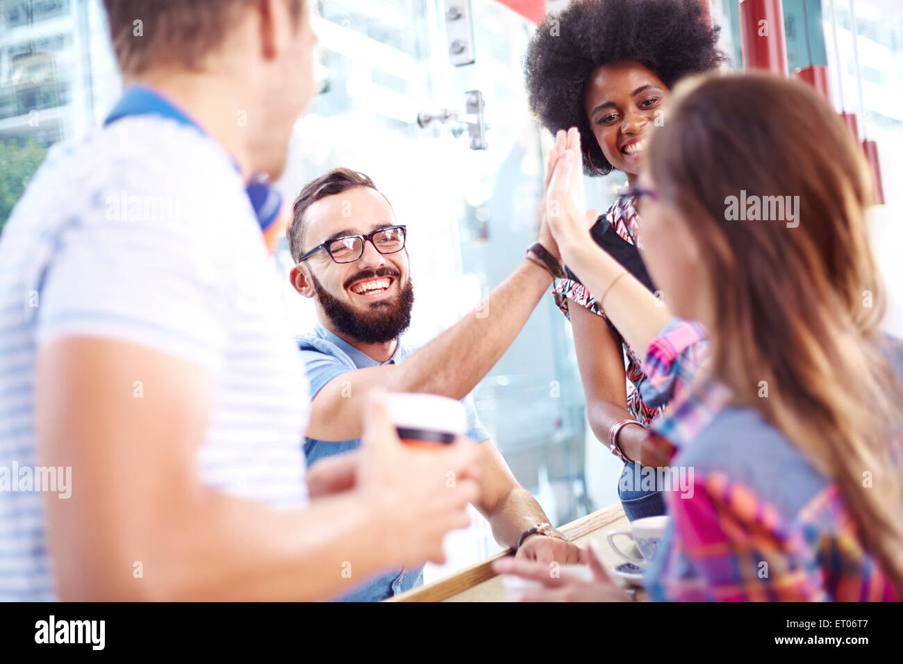 Friends high fiving in cafe Stock Photo - Alamy