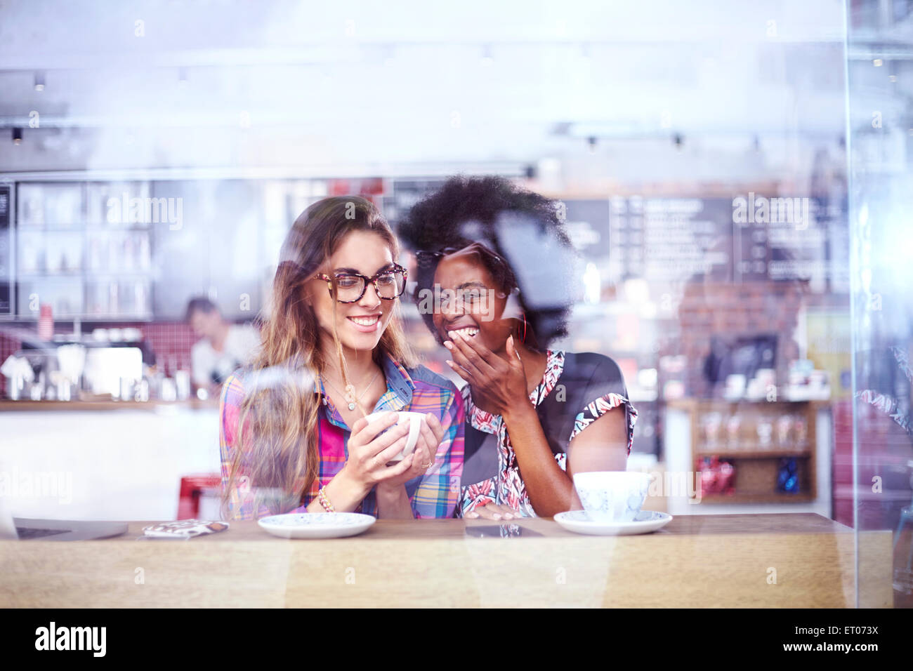 Women laughing and drinking coffee in cafe window Stock Photo - Alamy