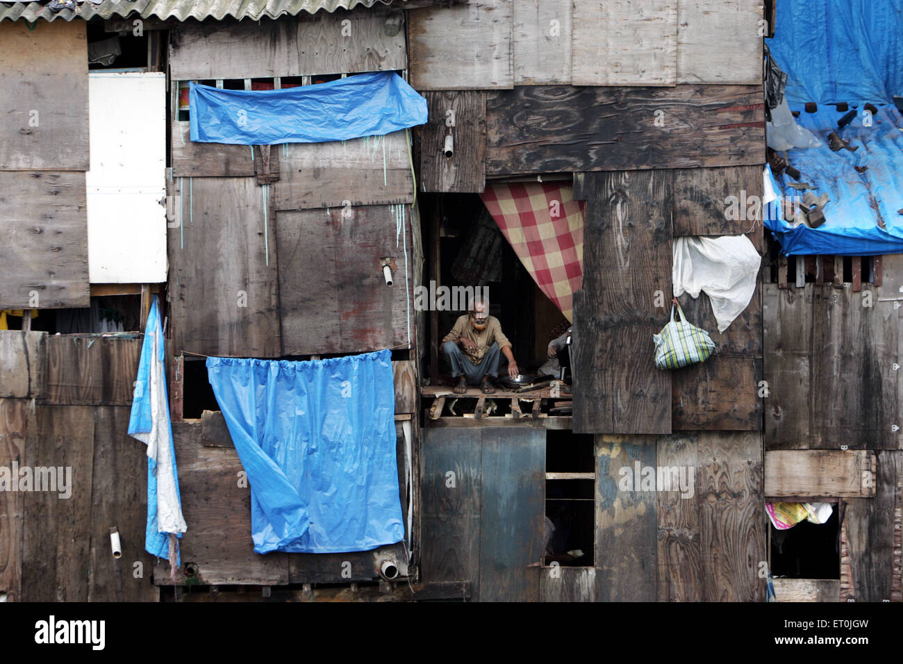 An old man can be seen sitting at a door Behrampada slum in Bandra ...