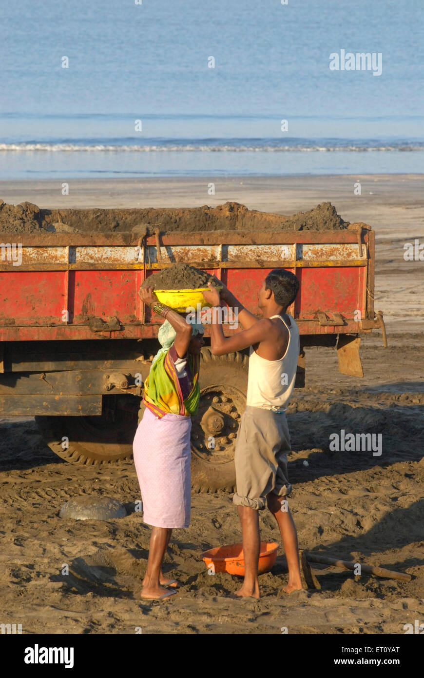 Workers lifting sand at Kalamb beach water of Arabian sea behind ...