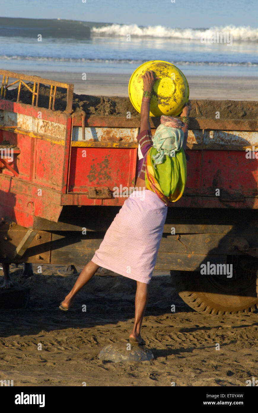Female worker lifting sand and filling trolley at Kalamb beach ...