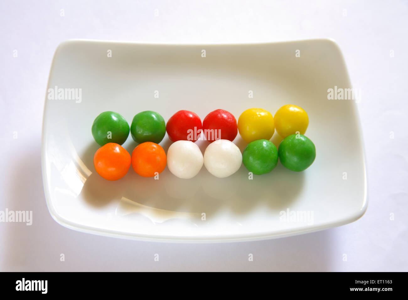 Colourful sweet and sour ball or marble in rectangle plate on white ...