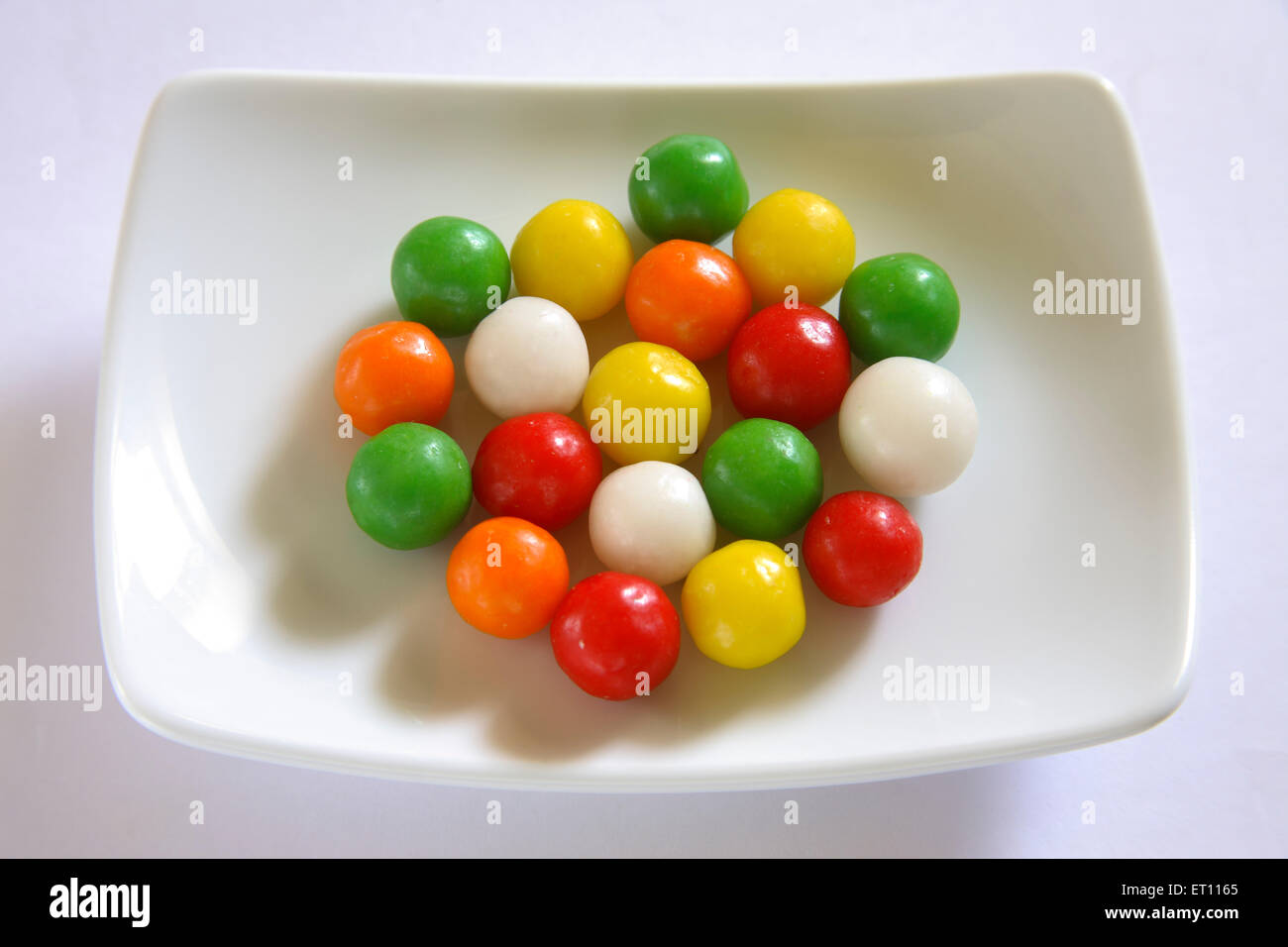 Colourful sweet and sour ball or marble in rectangle plate on white ...