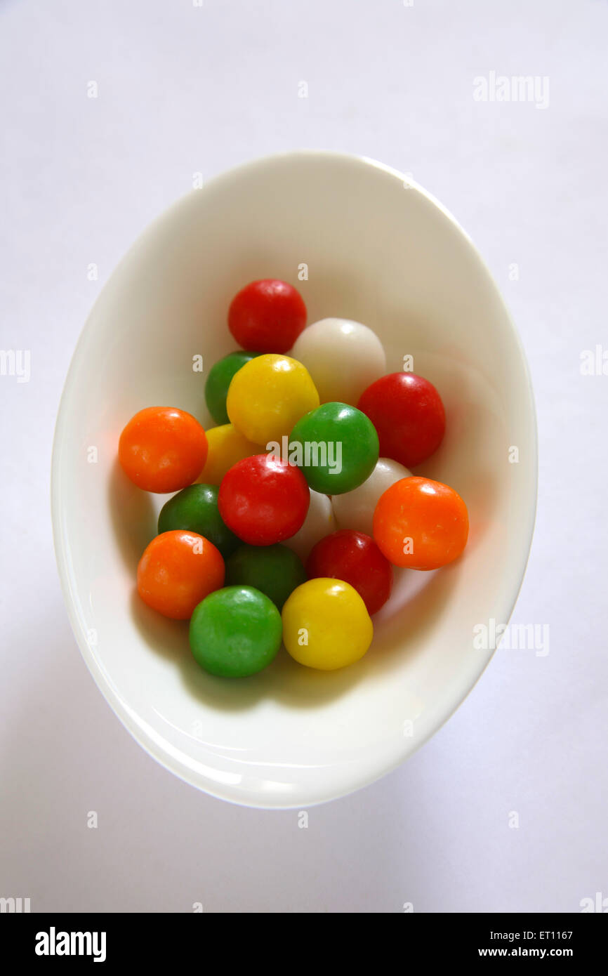 Colourful sweet and sour ball or marble in oval plate on white ...