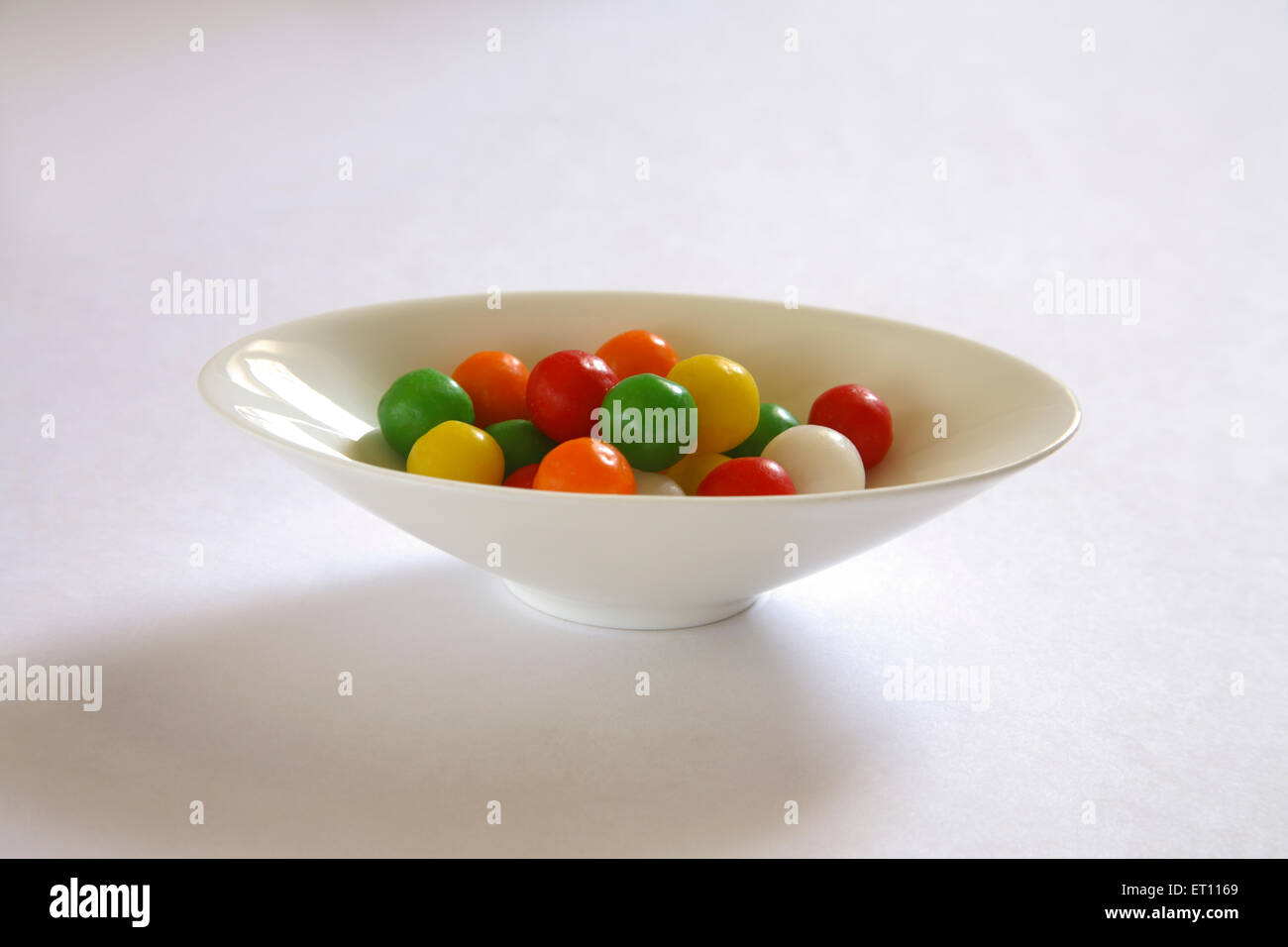 Colourful sweet and sour ball or marble in oval plate on white ...