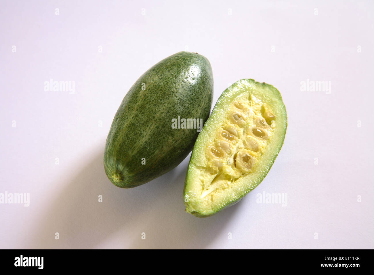 Vegetable ; one full and half striped pear gourds parwal on white ...