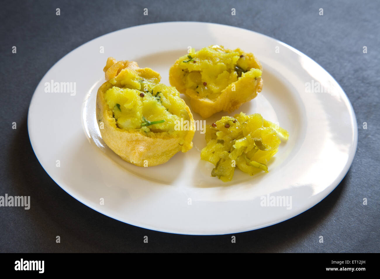 Indian fast food fried batata potato vada served with papaya chutney in ...