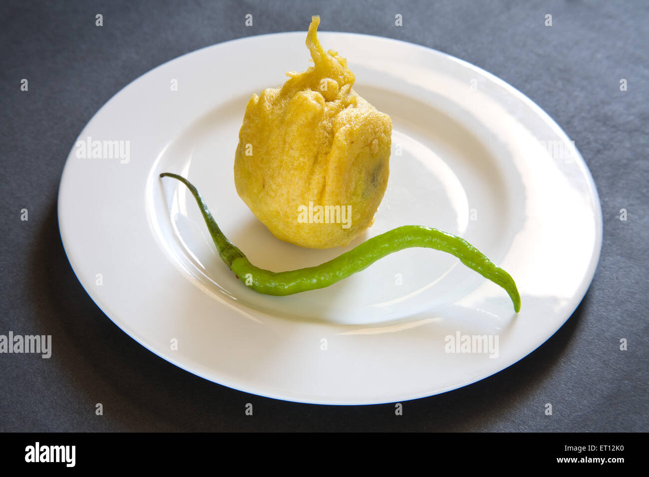 Indian fast food fried batata potato vada with green chilli served in ...