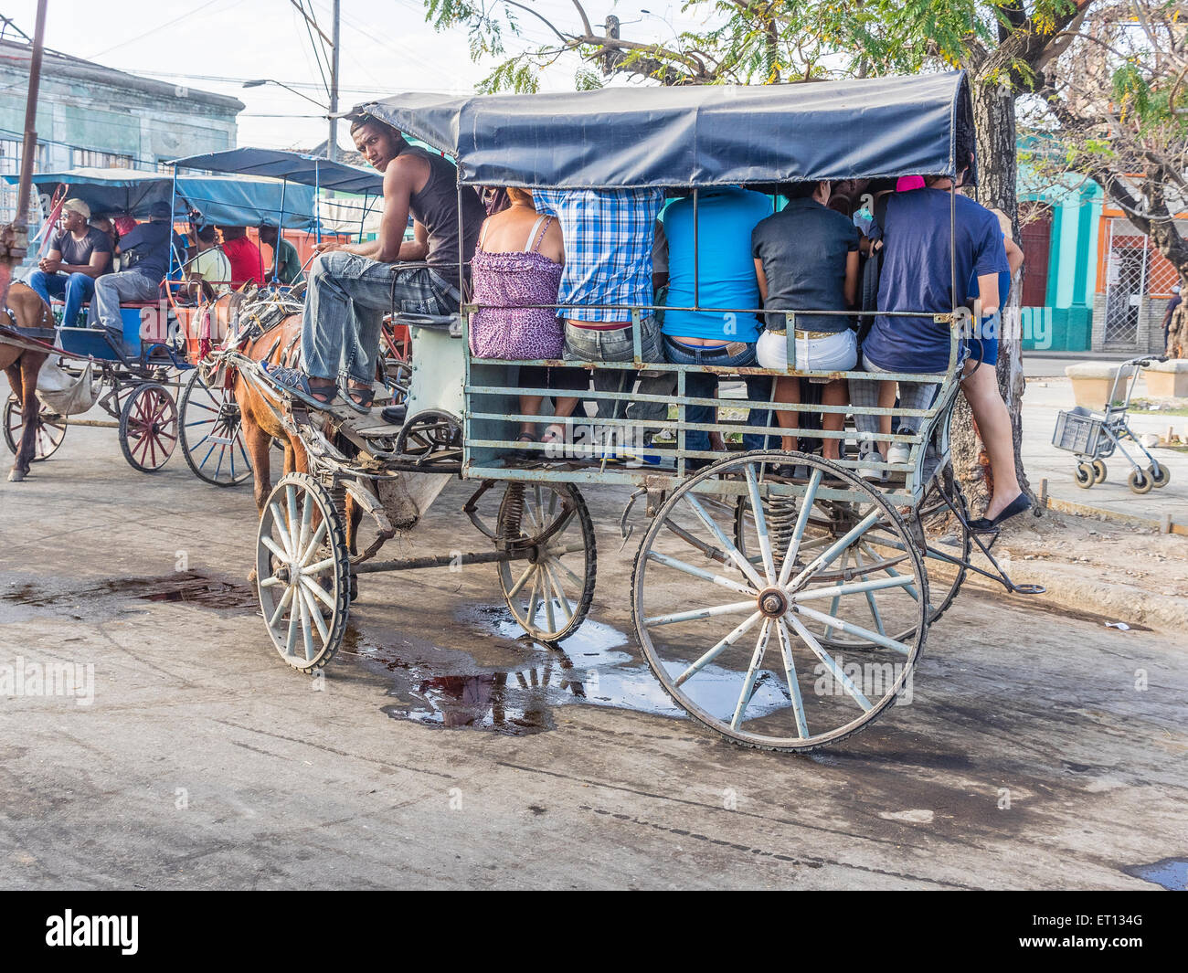 A crowded horse drawn carriage packed with commuters, serves as a ...