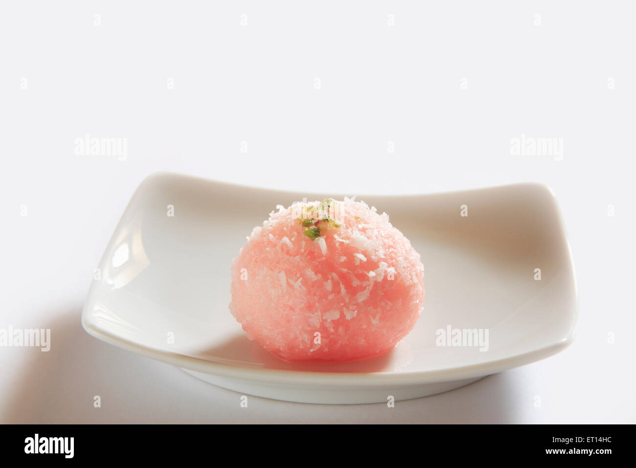 One piece of bengali mithai raskadam garnish with coconut and pistachio ...