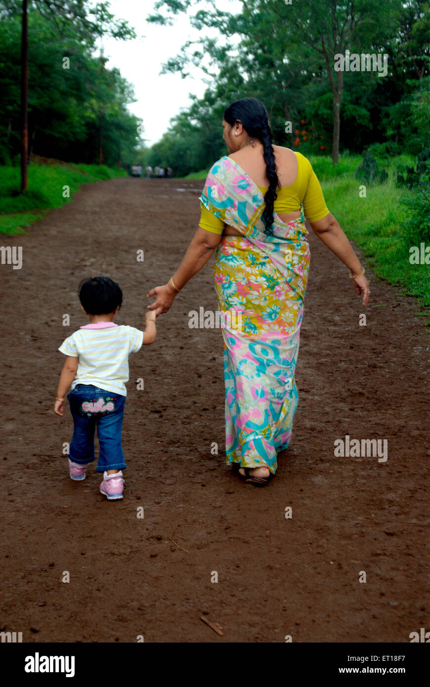 Indian Grandmother And Grandson Walking In Garden Holding Hands Mr